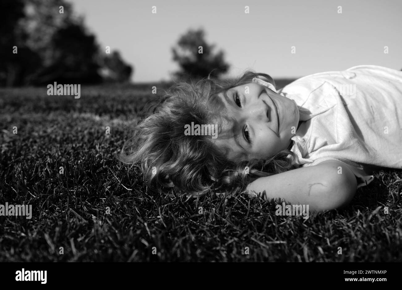 Sweet, happy child boy playing on a grass in a park at a spring ...