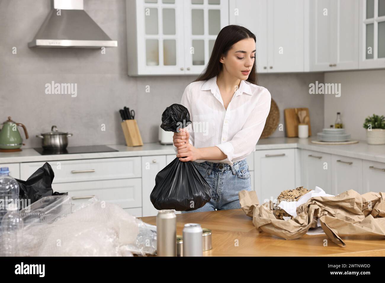 Garbage sorting. Woman with plastic bag at table in kitchen Stock Photo ...