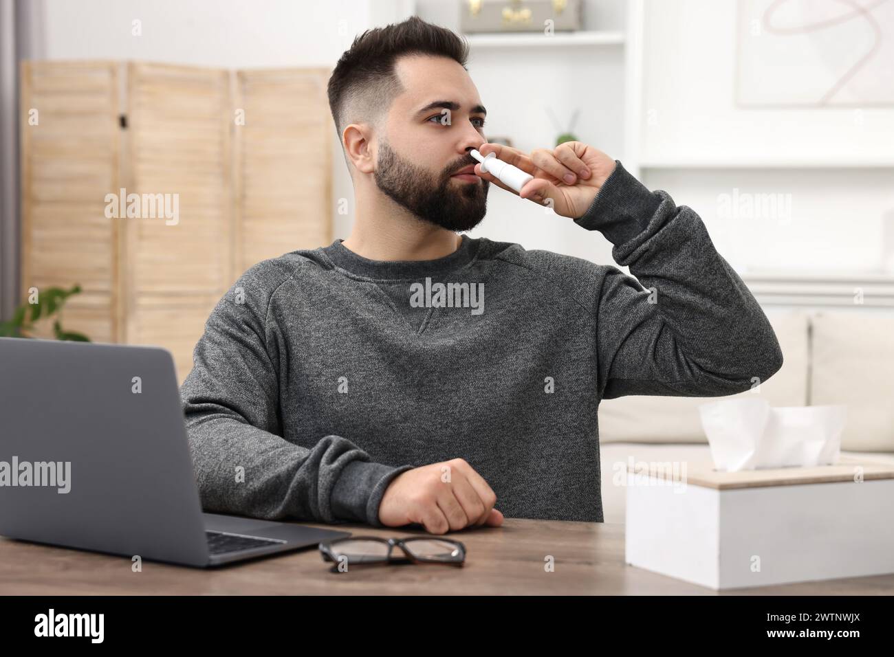 Medical drops. Young man using nasal spray at table indoors Stock Photo ...