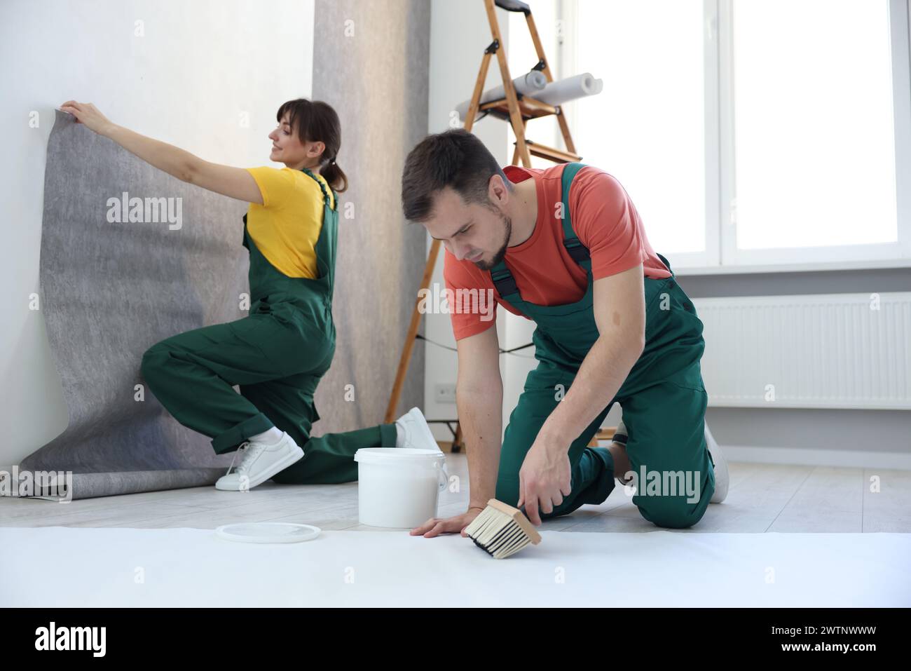 Workers hanging stylish gray wallpaper in room Stock Photo - Alamy