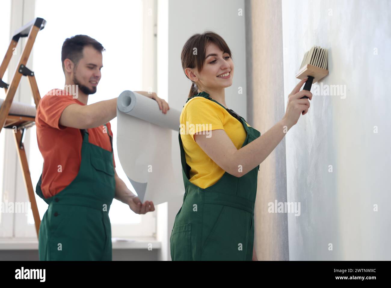 Workers hanging stylish gray wallpaper in room Stock Photo - Alamy