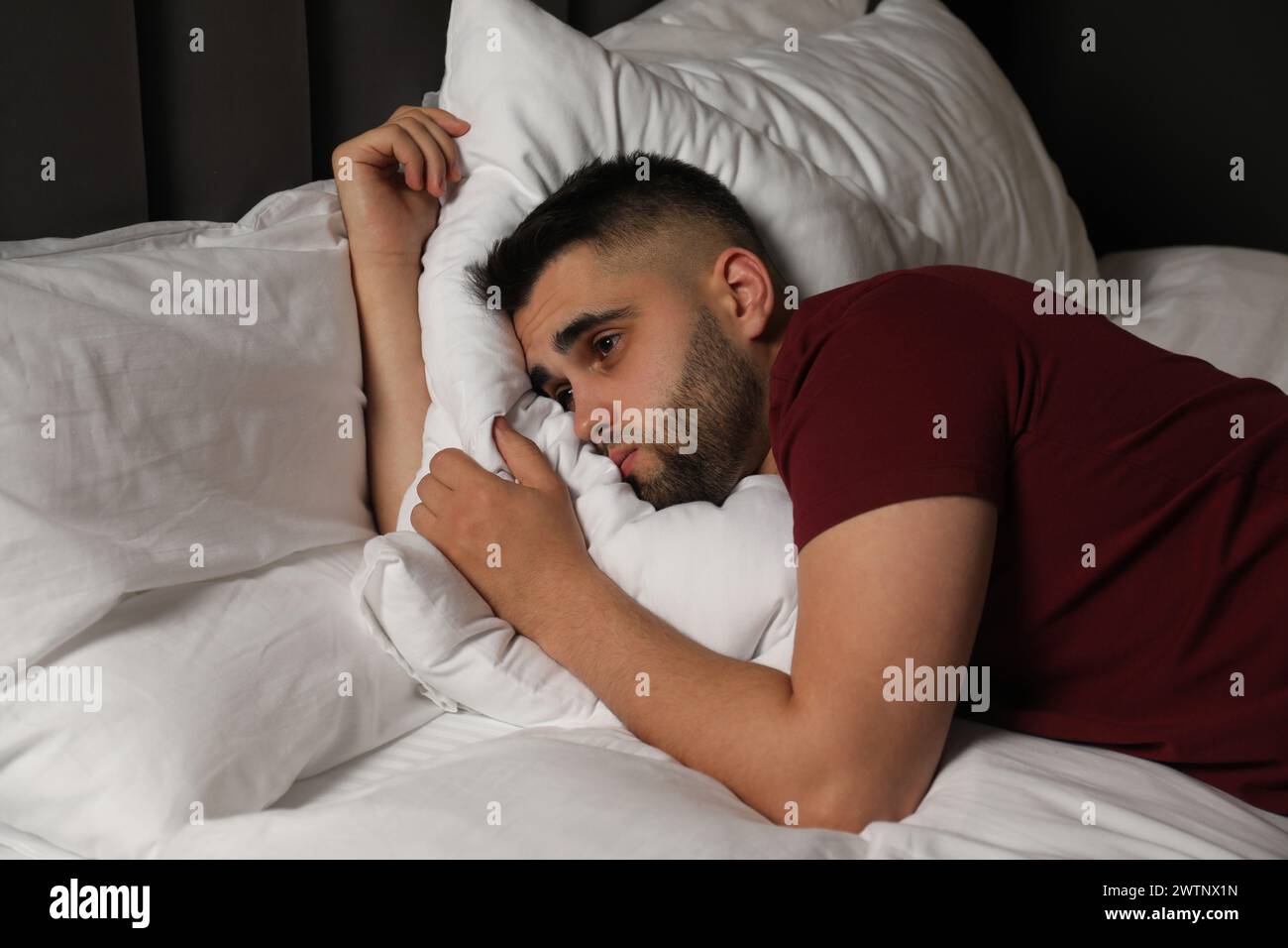 Sad man lying on bed at home Stock Photo - Alamy