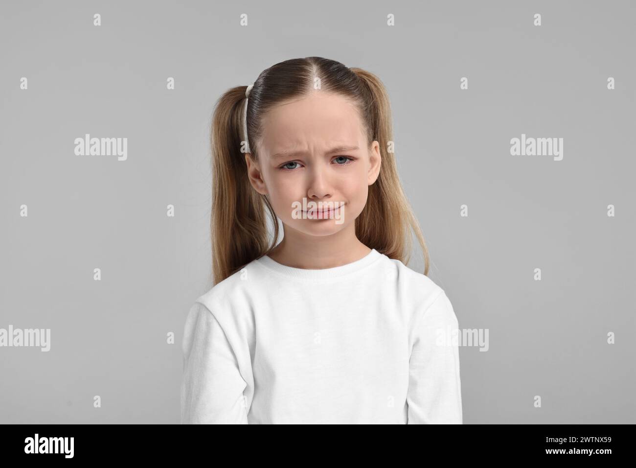 Portrait of sad girl on light grey background Stock Photo - Alamy