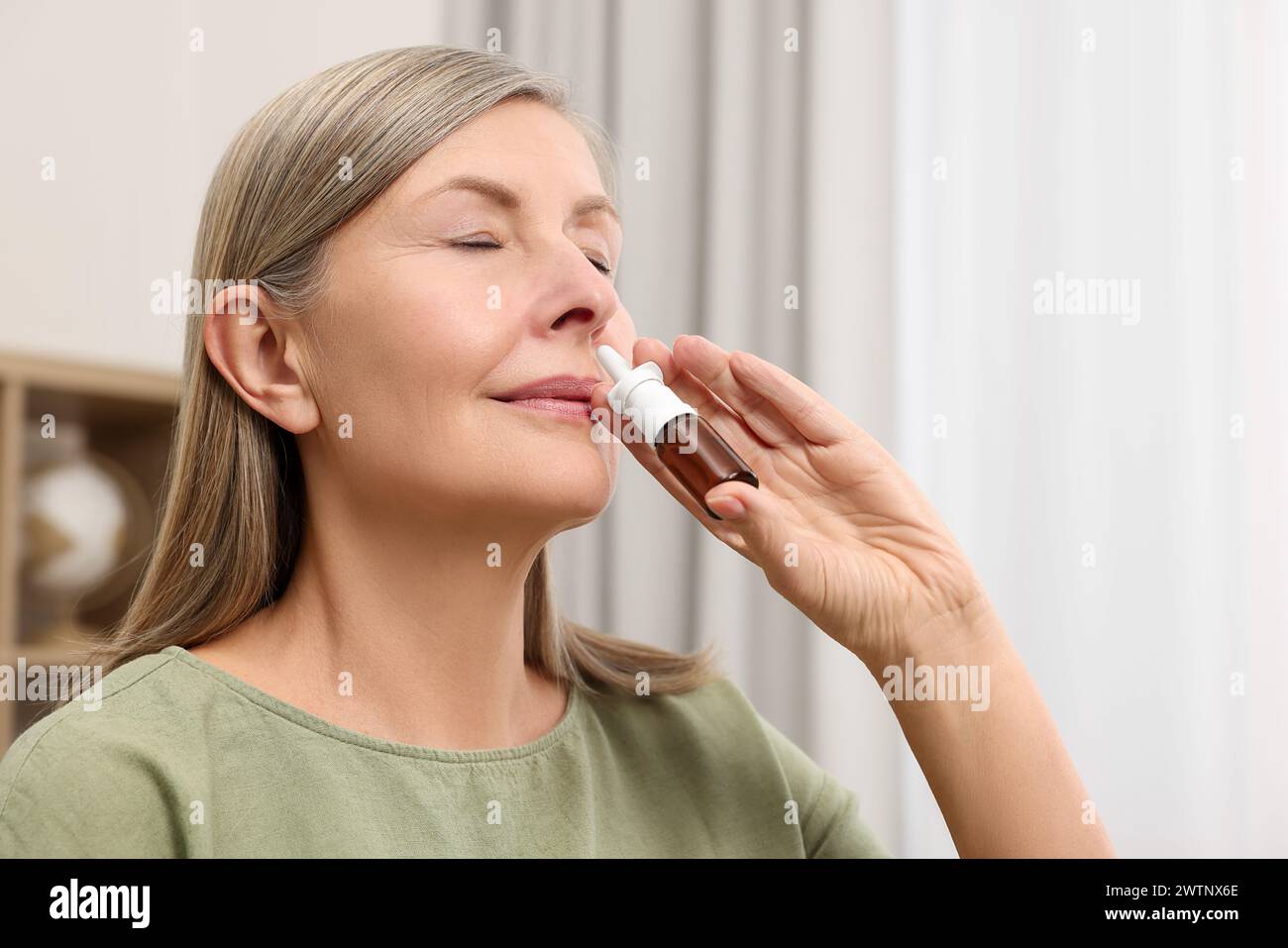 Medical drops. Woman using nasal spray indoors Stock Photo - Alamy
