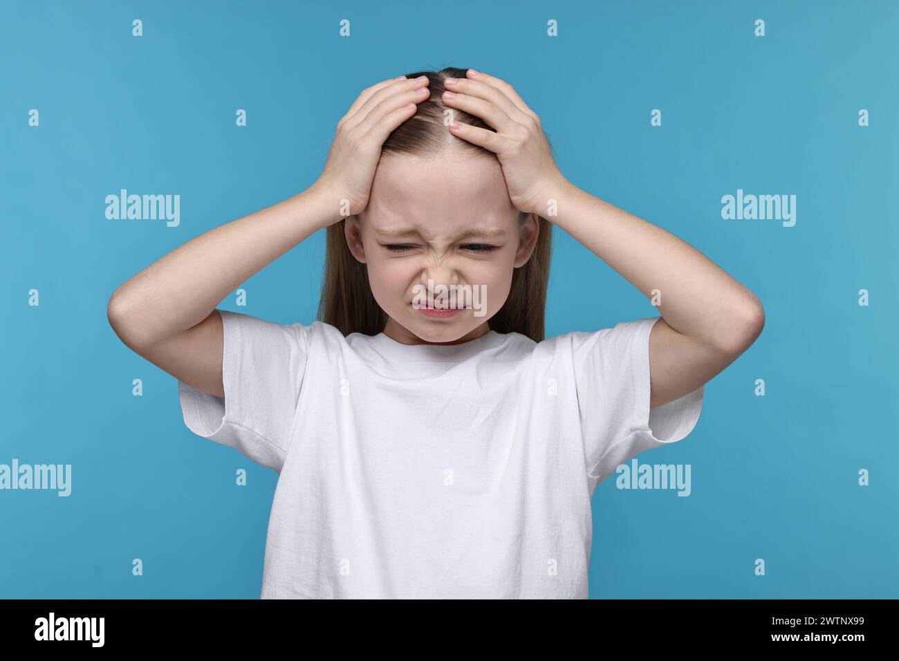 Little girl suffering from headache on light blue background Stock ...