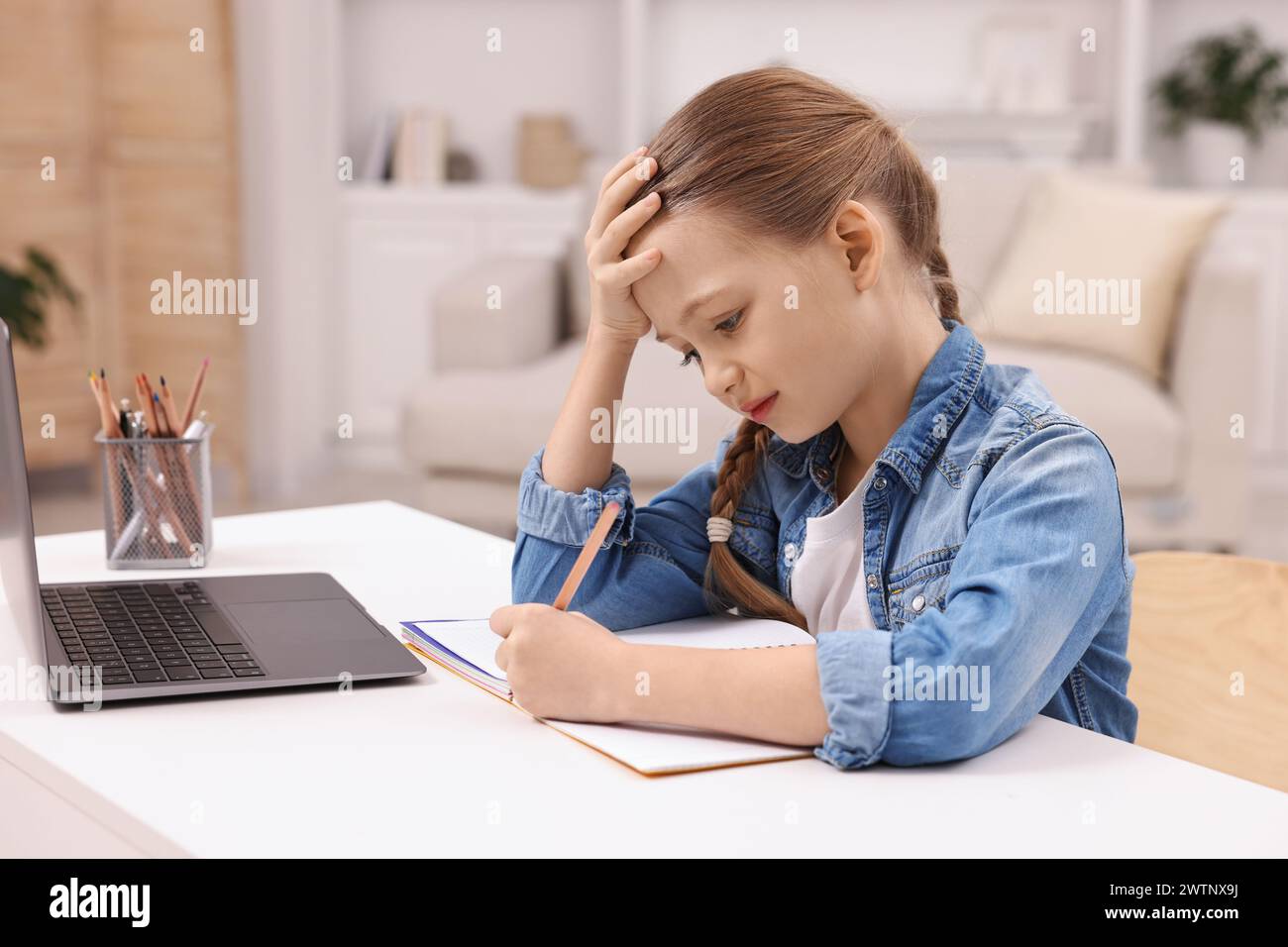 Little girl suffering from headache while doing homework at home Stock ...