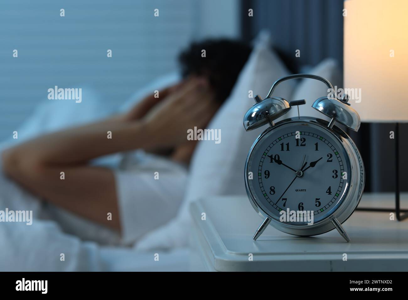 Woman suffering from headache in bed at night, focus on alarm clock ...
