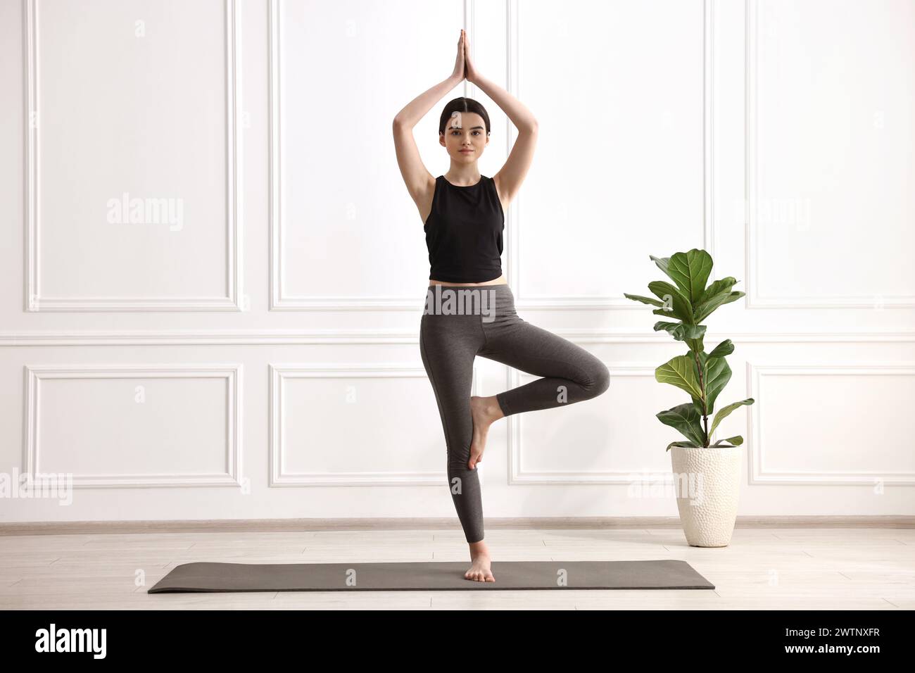 Girl practicing tree asana on mat in yoga studio. Vrksasana pose Stock ...