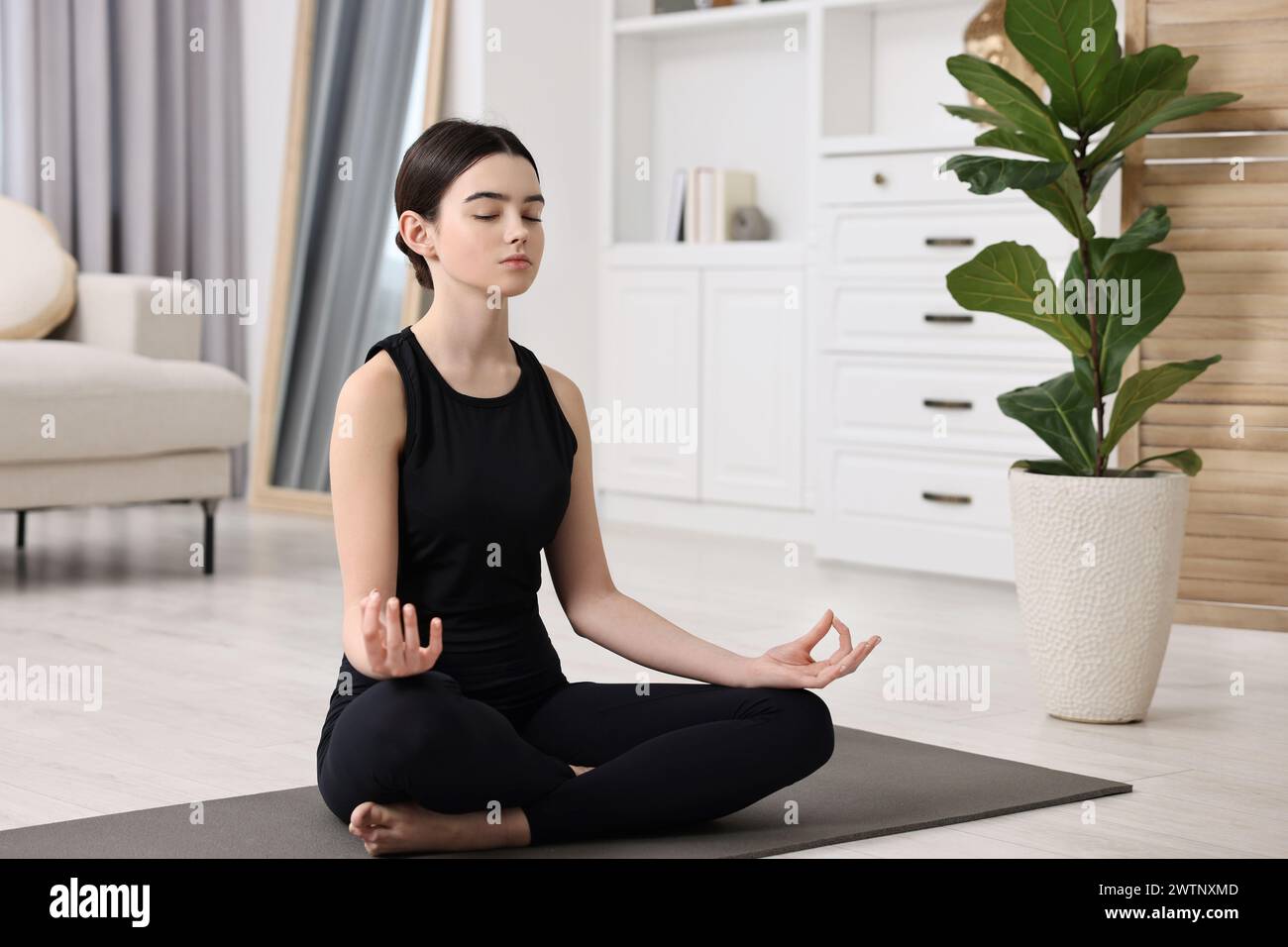 Beautiful girl meditating on yoga mat at home Stock Photo - Alamy