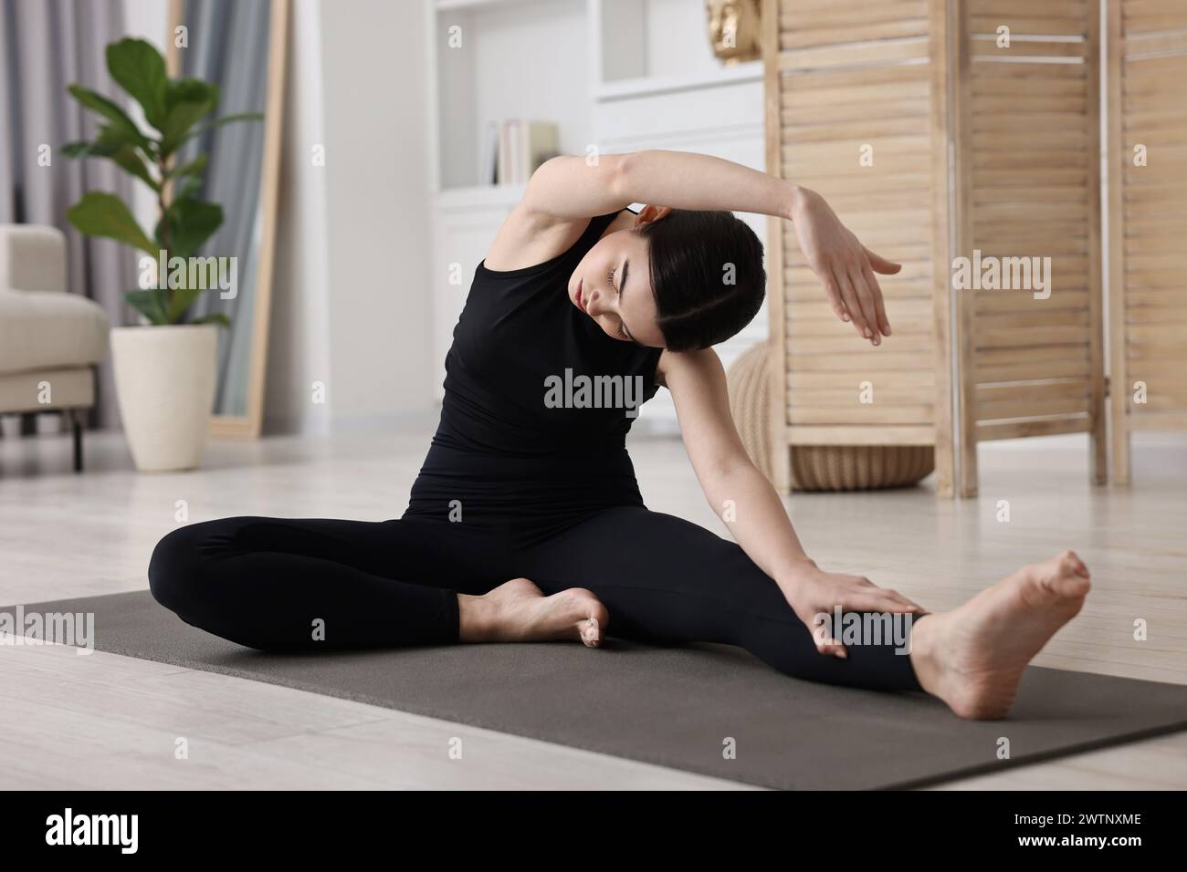 Girl practicing revolved head to knee asana on yoga mat at home ...