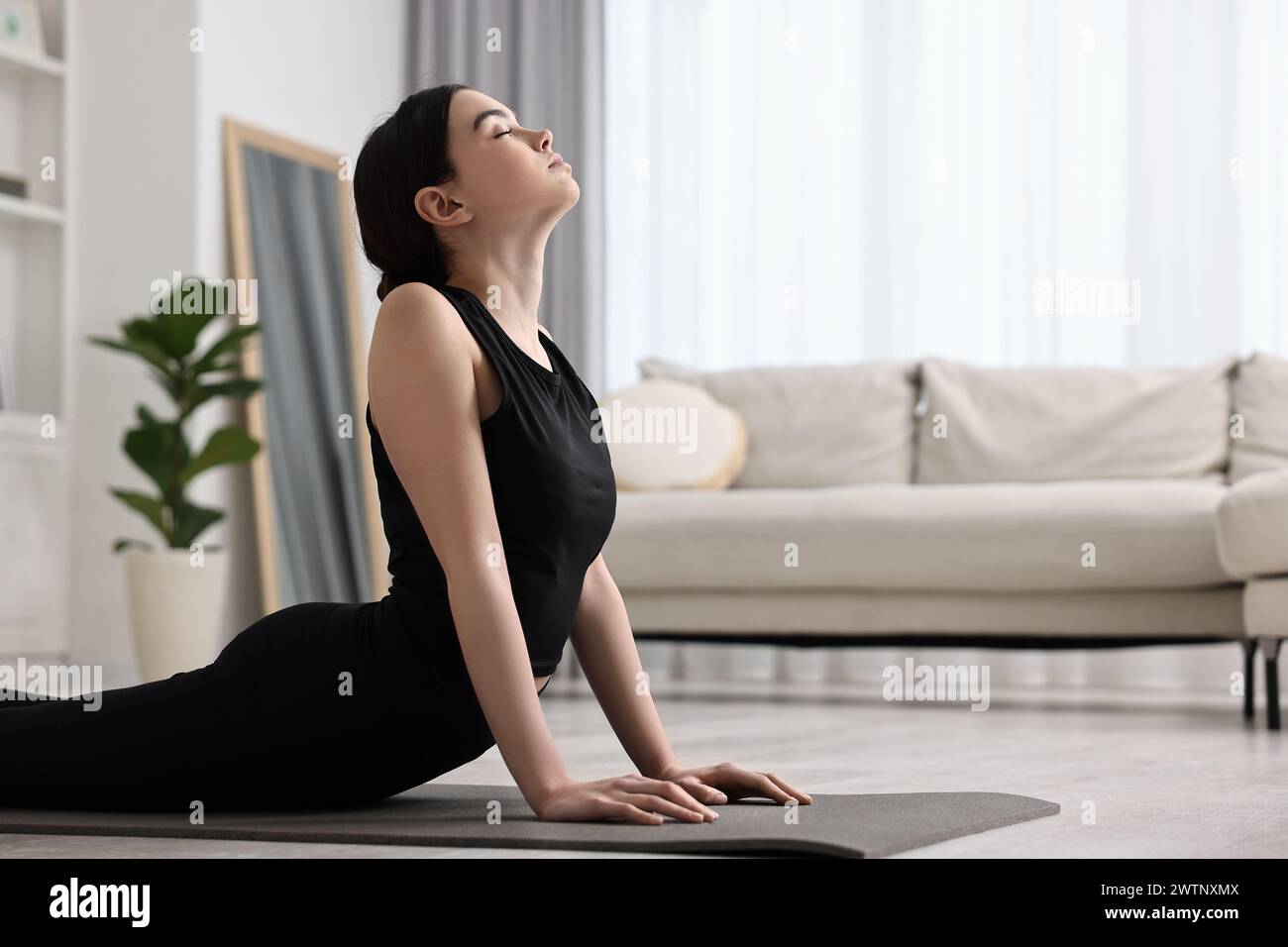 Girl practicing cobra asana on yoga mat at home. Bhujangasana pose ...