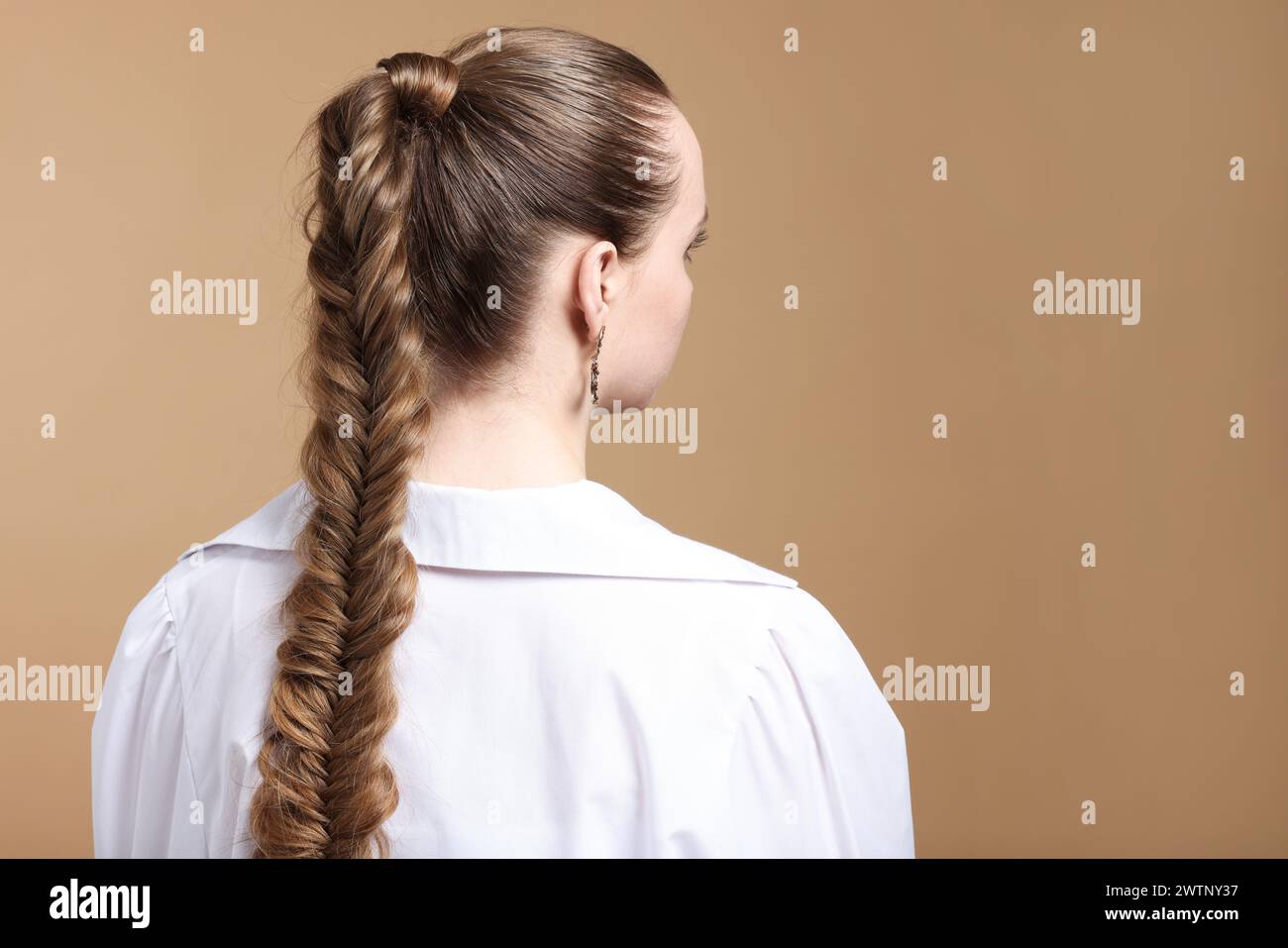 Woman with braided hair on brown background, back view. Space for text ...