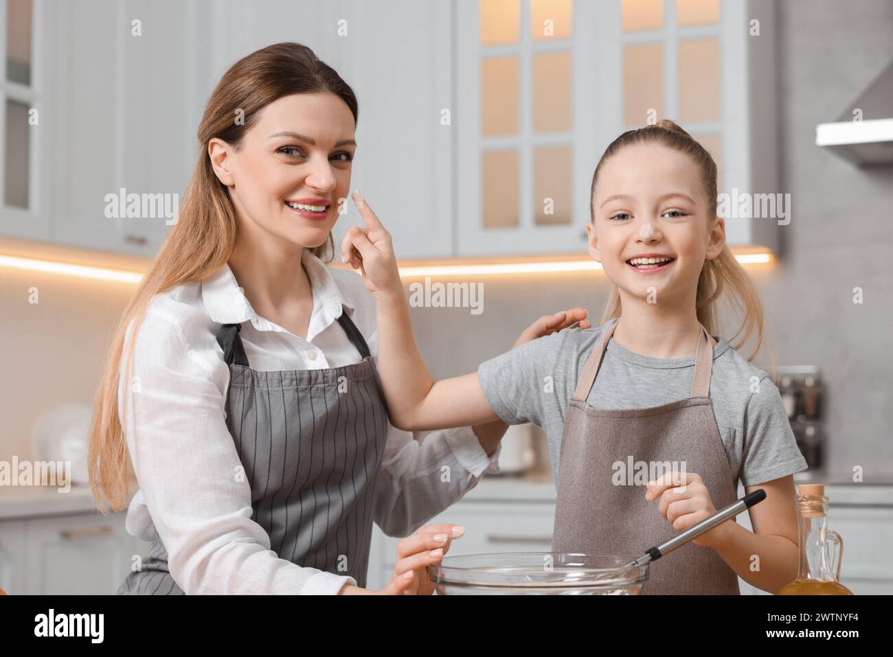 Making bread. Mother and her daughter preparing dough at wooden table ...