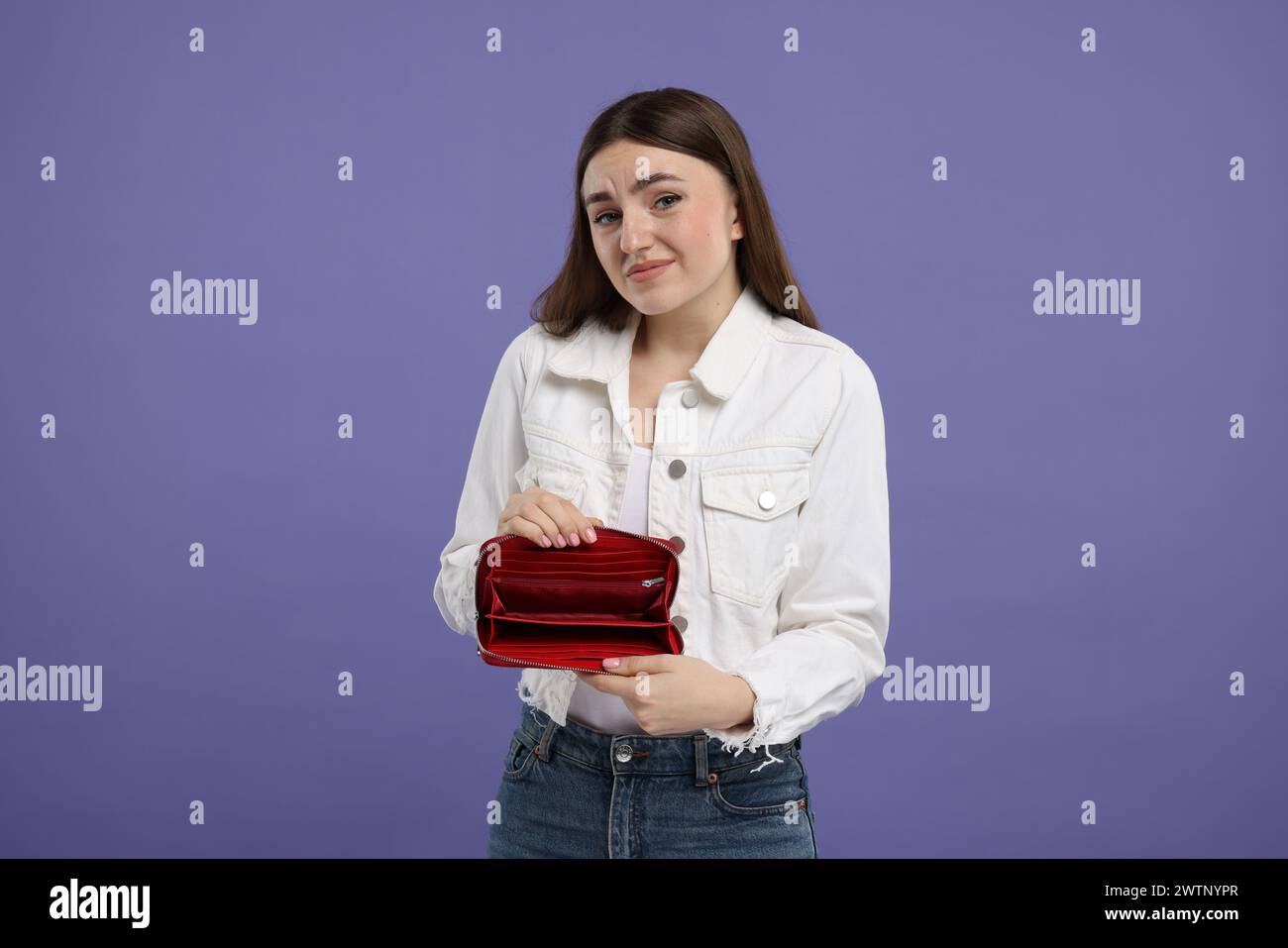 Sad woman showing empty wallet on purple background Stock Photo - Alamy