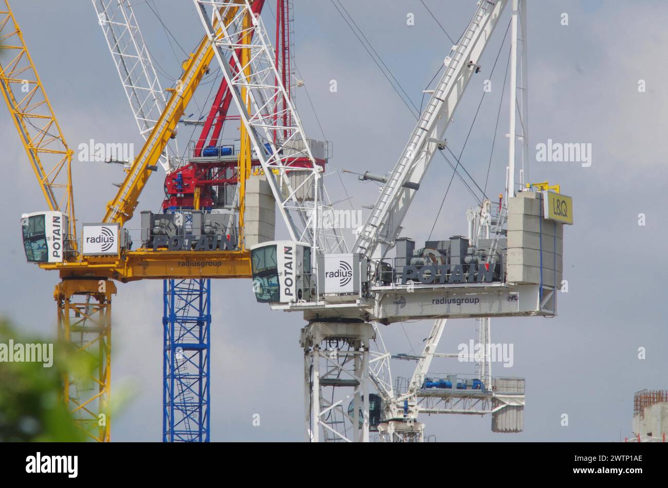 Four luffing cranes in use on a construction site. Showing the winding ...