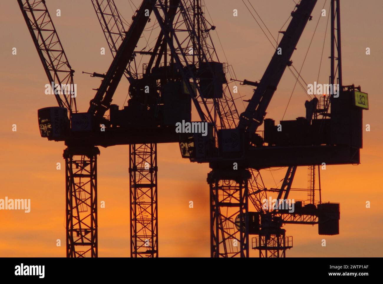 Silhouettes of four luffing cranes in use on a construction site at ...