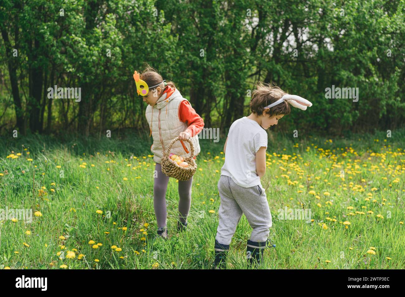 Two children hunt for Easter eggs in a spring garden. Easter tradition ...
