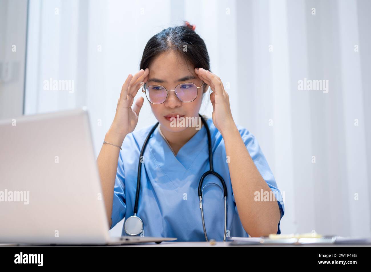 A stressed, overworked, and tired Asian female doctor is reading her ...