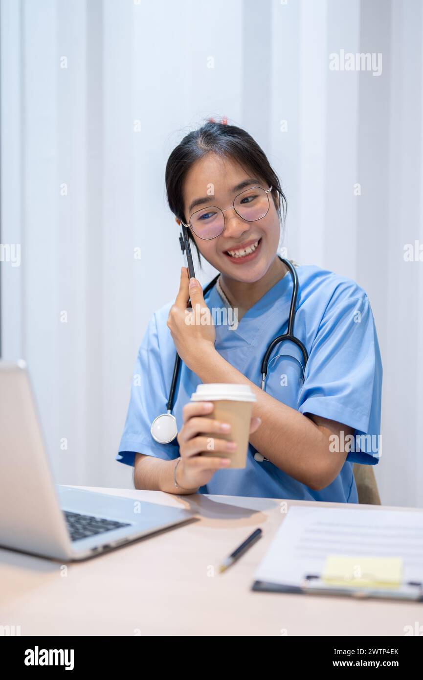 A positive, hardworking Asian female doctor is multitasking, talking on ...
