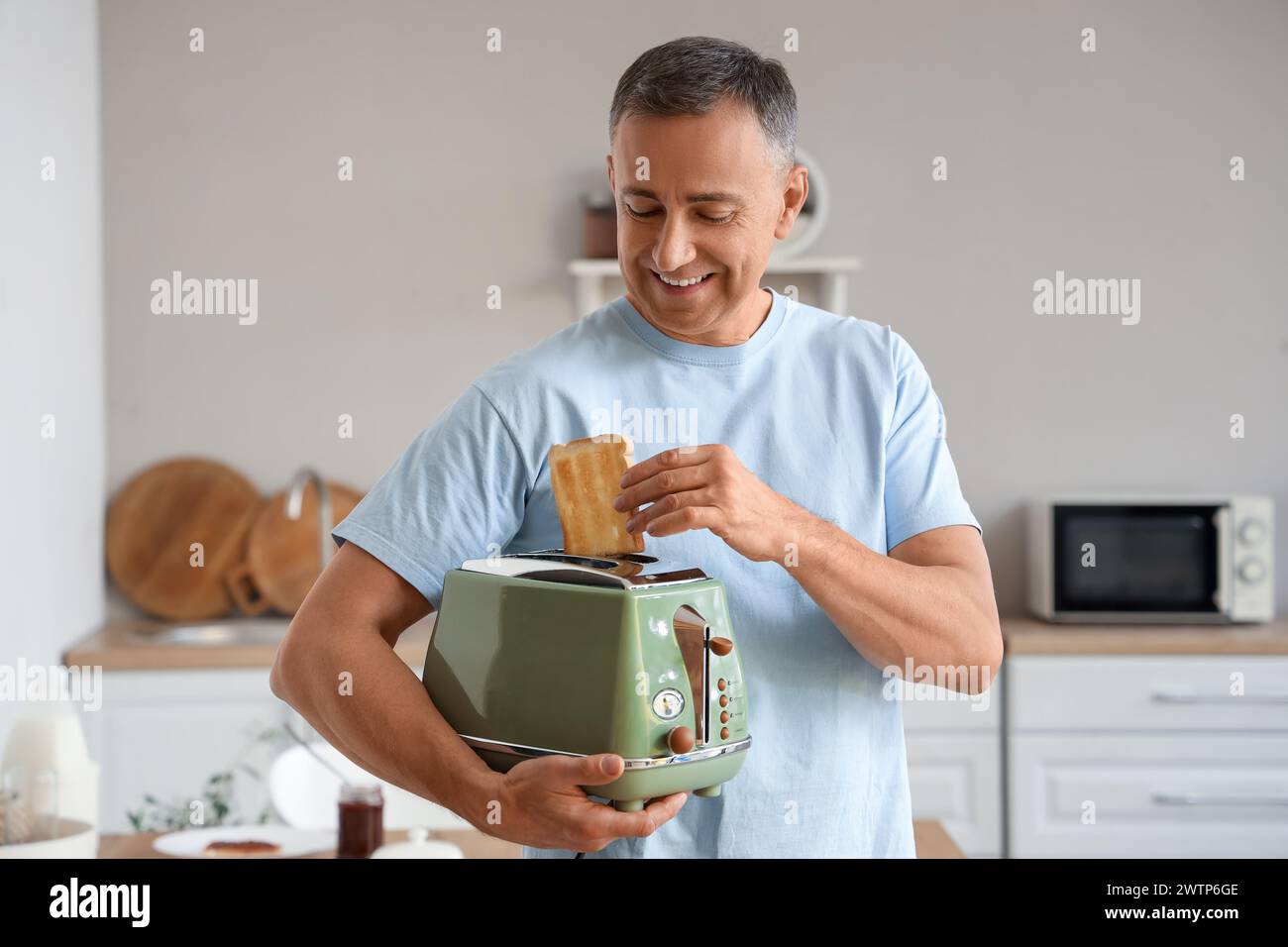 Middle-aged man with modern toaster and crispy toast in kitchen Stock ...