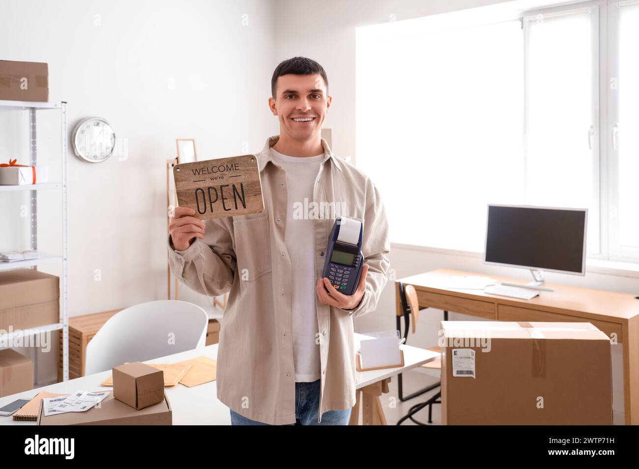 Male online store seller with OPEN sign and payment terminal in ...