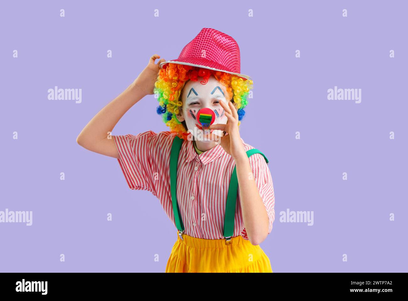 Funny little girl dressed as clown with party blower on lilac ...