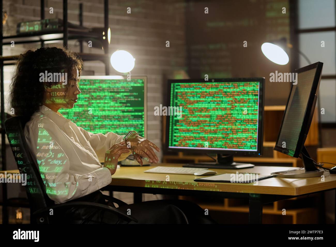 Female African-American programmer looking at smartwatch in office ...