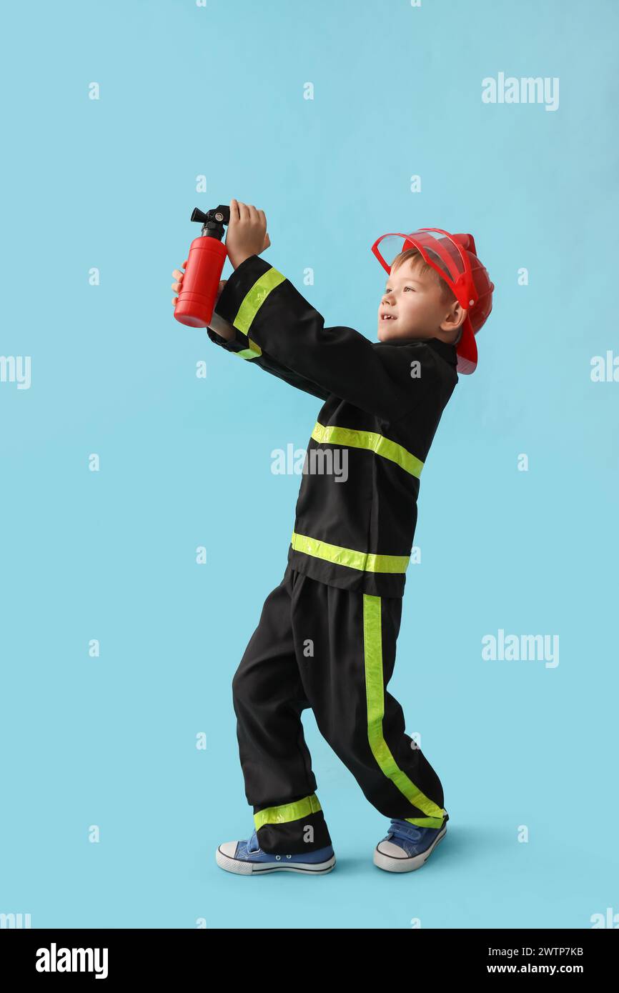 Cute little firefighter with toy extinguisher on blue background Stock ...