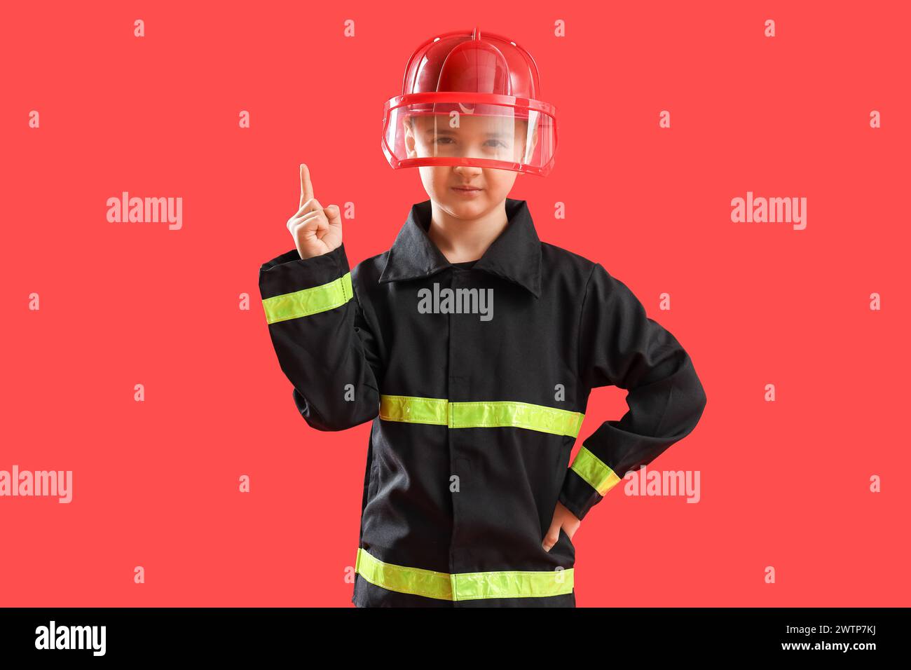 Cute little firefighter pointing at something on red background Stock ...