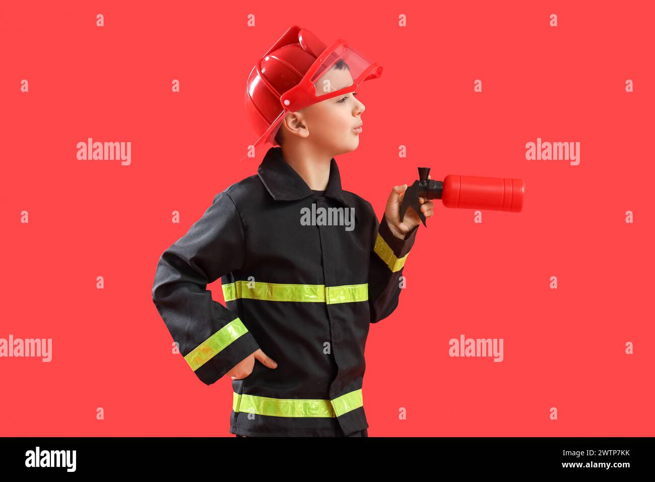 Cute little firefighter with toy extinguisher on red background Stock ...