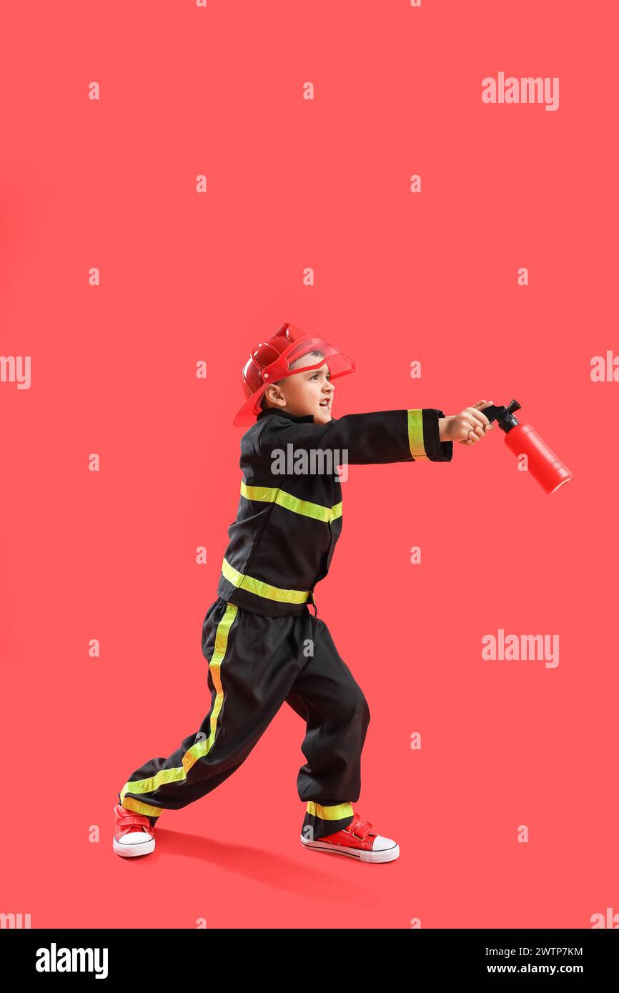 Cute little firefighter with toy extinguisher on red background Stock ...