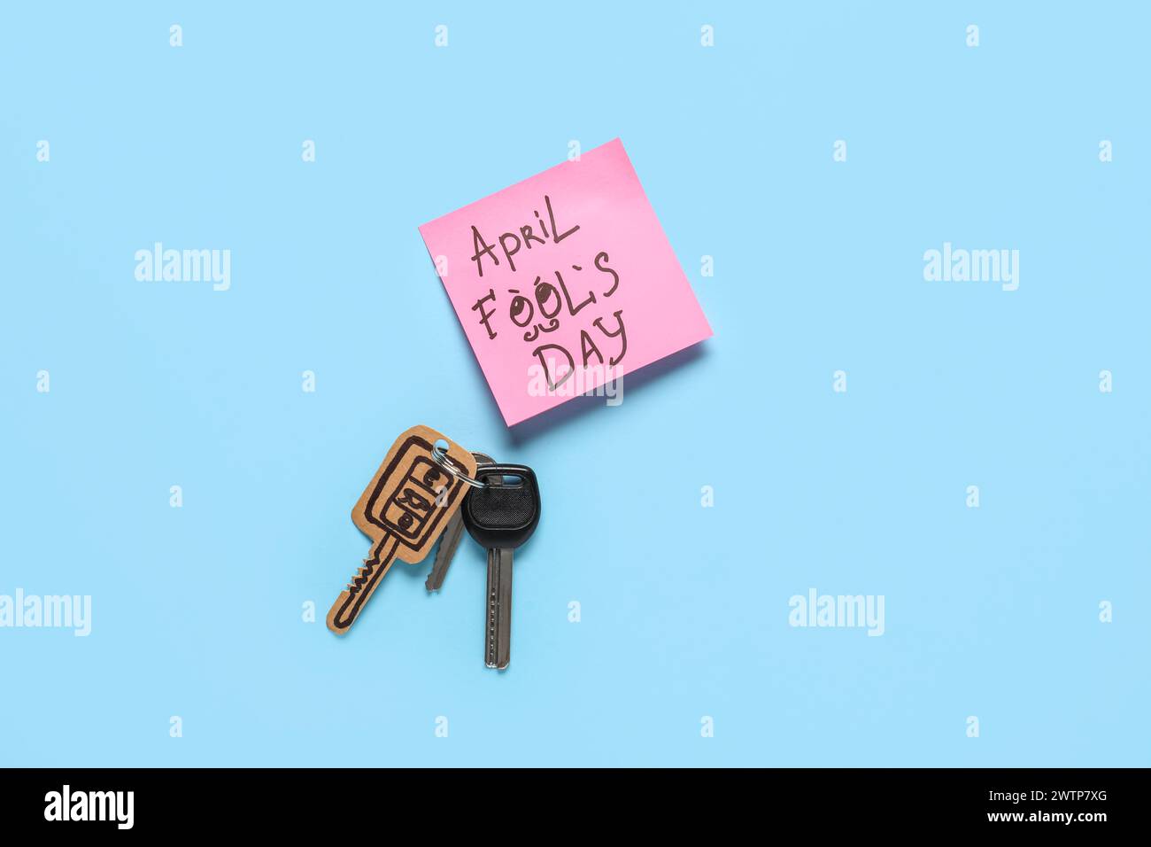 Sticky note and carton key on blue background. April Fools Day prank ...