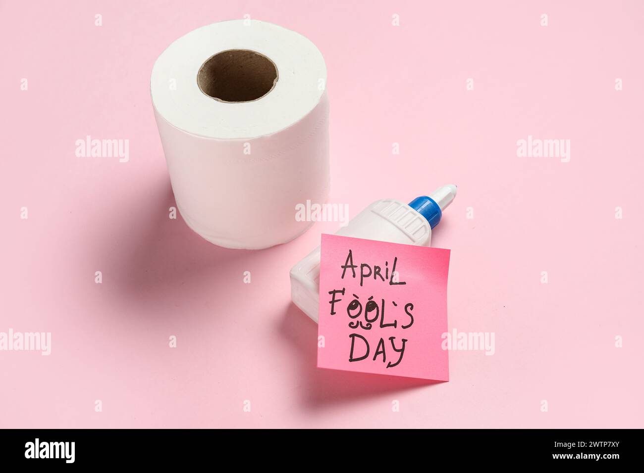 Toilet paper, glue and sticky note on pink background. April Fools Day ...