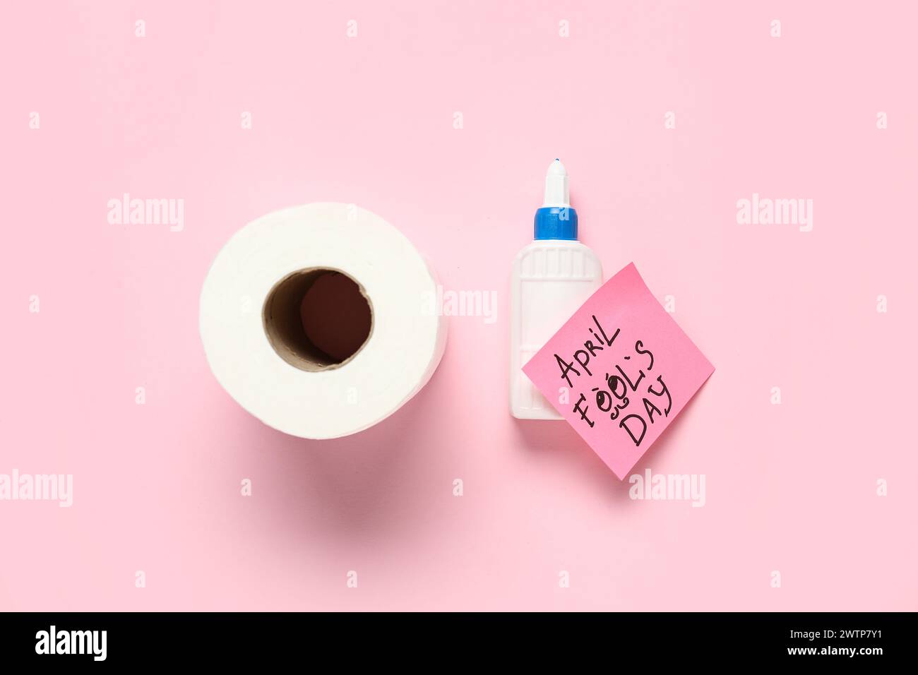 Toilet paper, glue and sticky note on pink background. April Fools Day ...