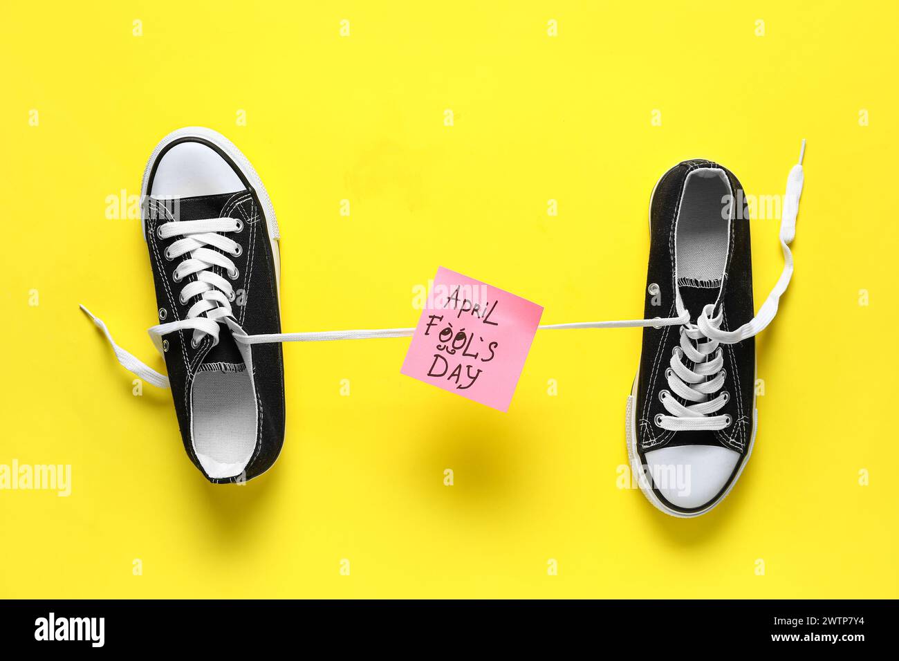 Shoes with tied together laces and sticky note on yellow background ...