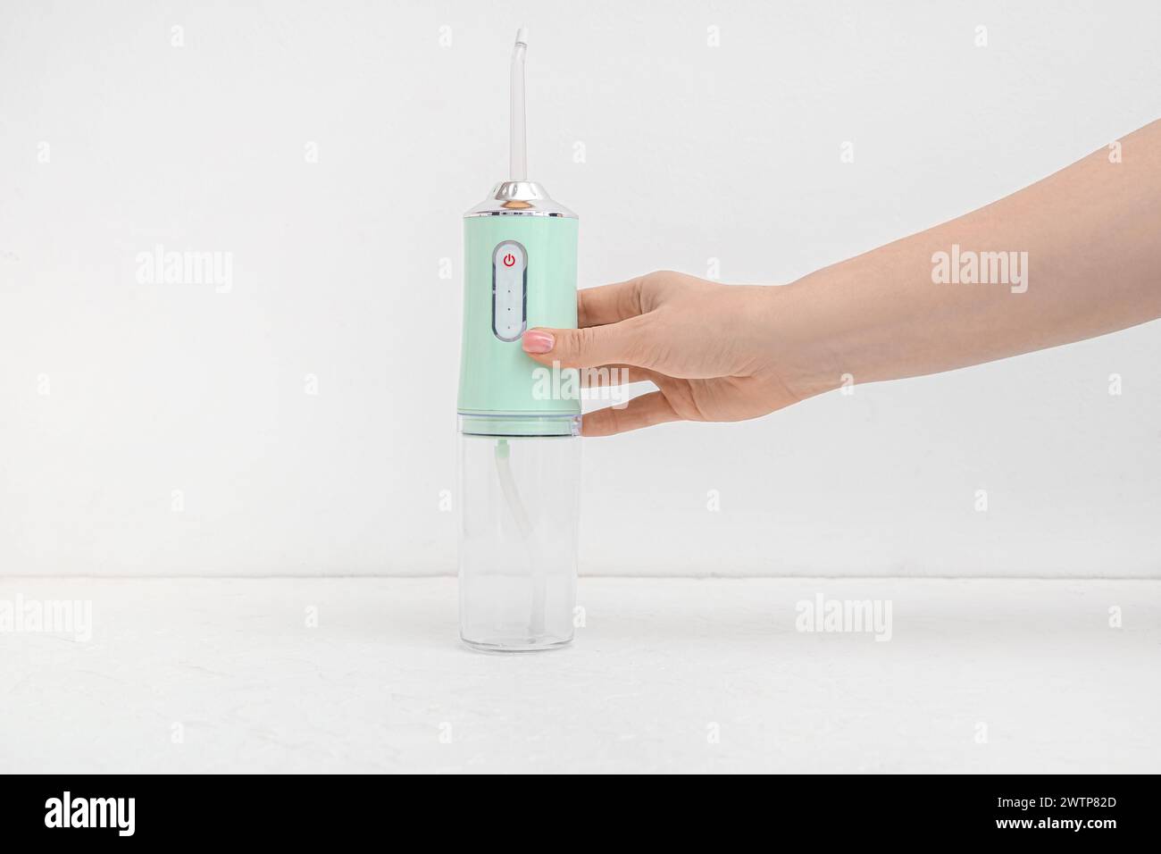 Female hand holding oral irrigator on white background Stock Photo - Alamy