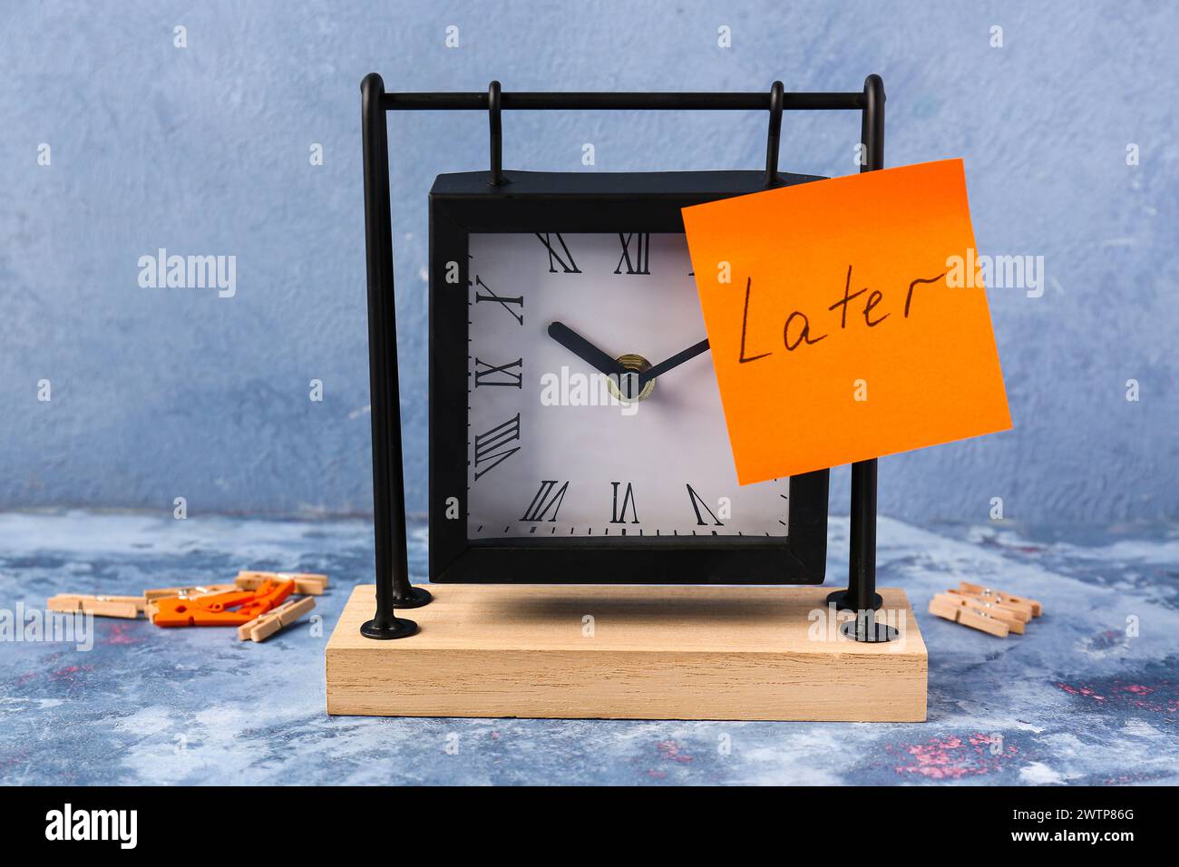 Text LATER with black alarm clock on table against blue background ...