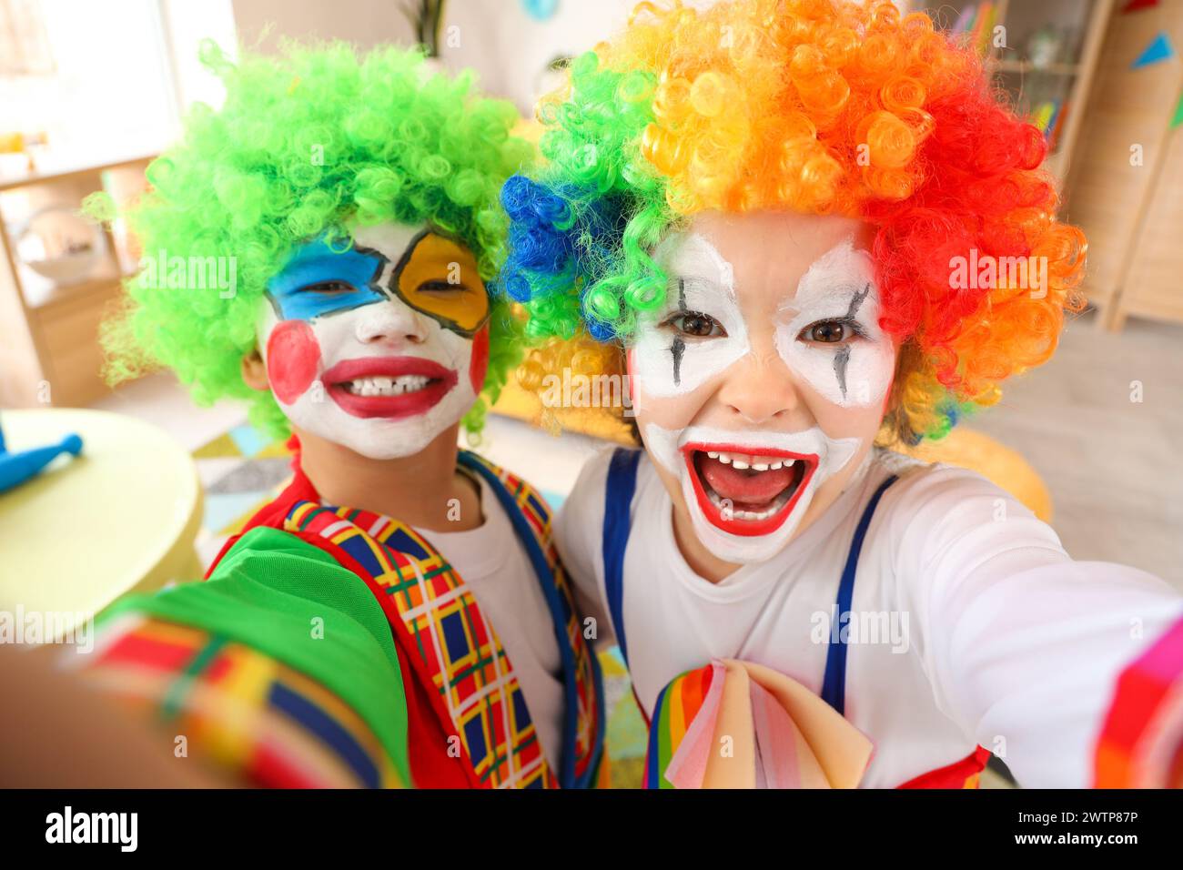 Funny little children in clown costumes at home, closeup. April Fools ...
