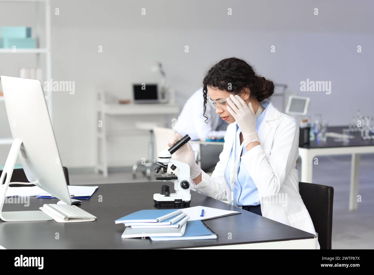 Female African-American chemist working with microscope at table in ...