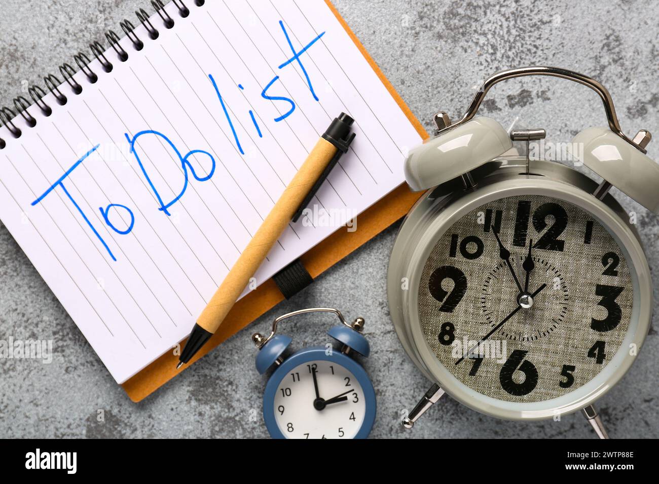 Notebook with text TO DO LIST, alarm clocks and pen on grunge ...