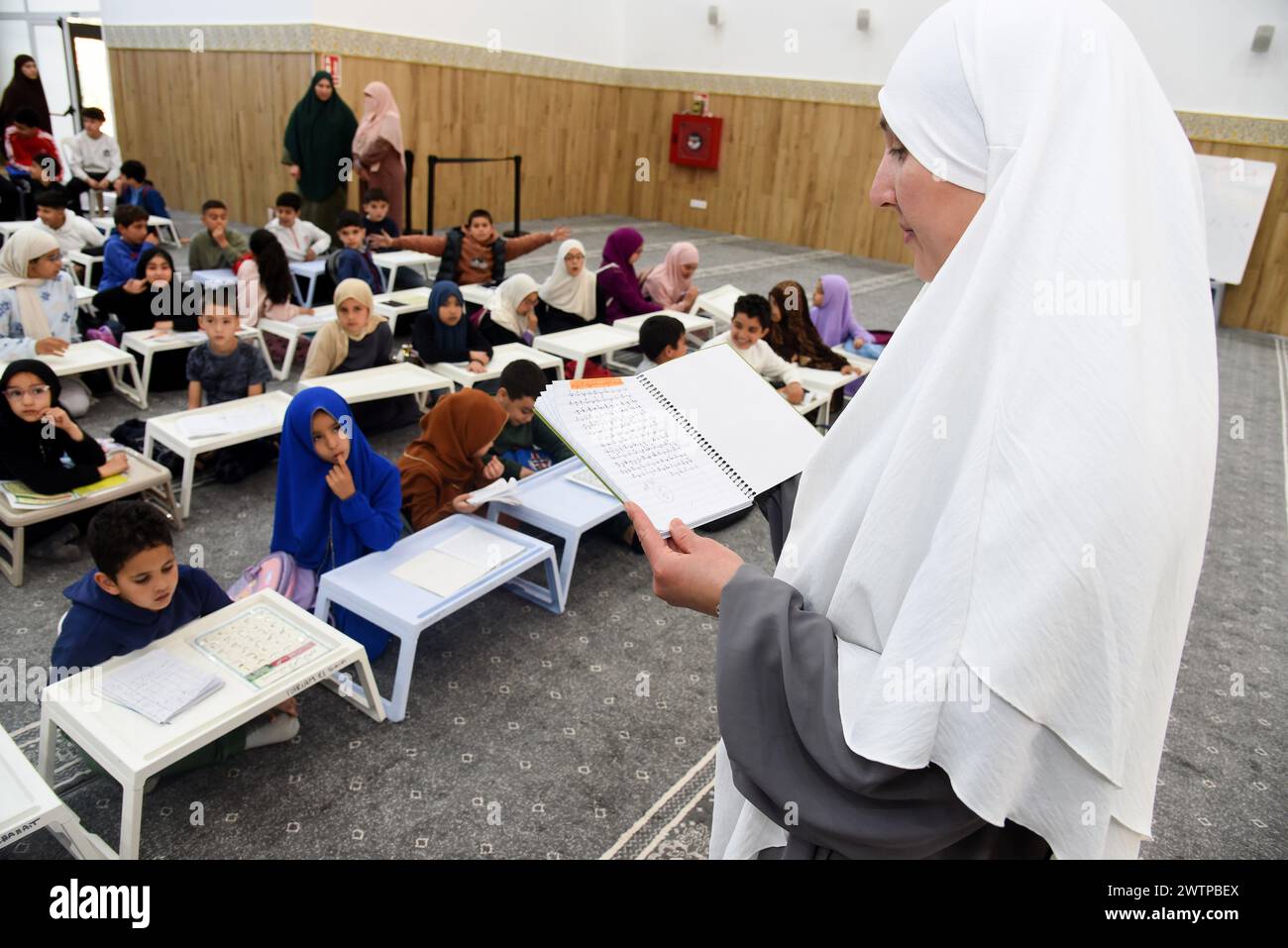 An Arabic teacher wearing an Islamic veil corrects a text in Arabic ...