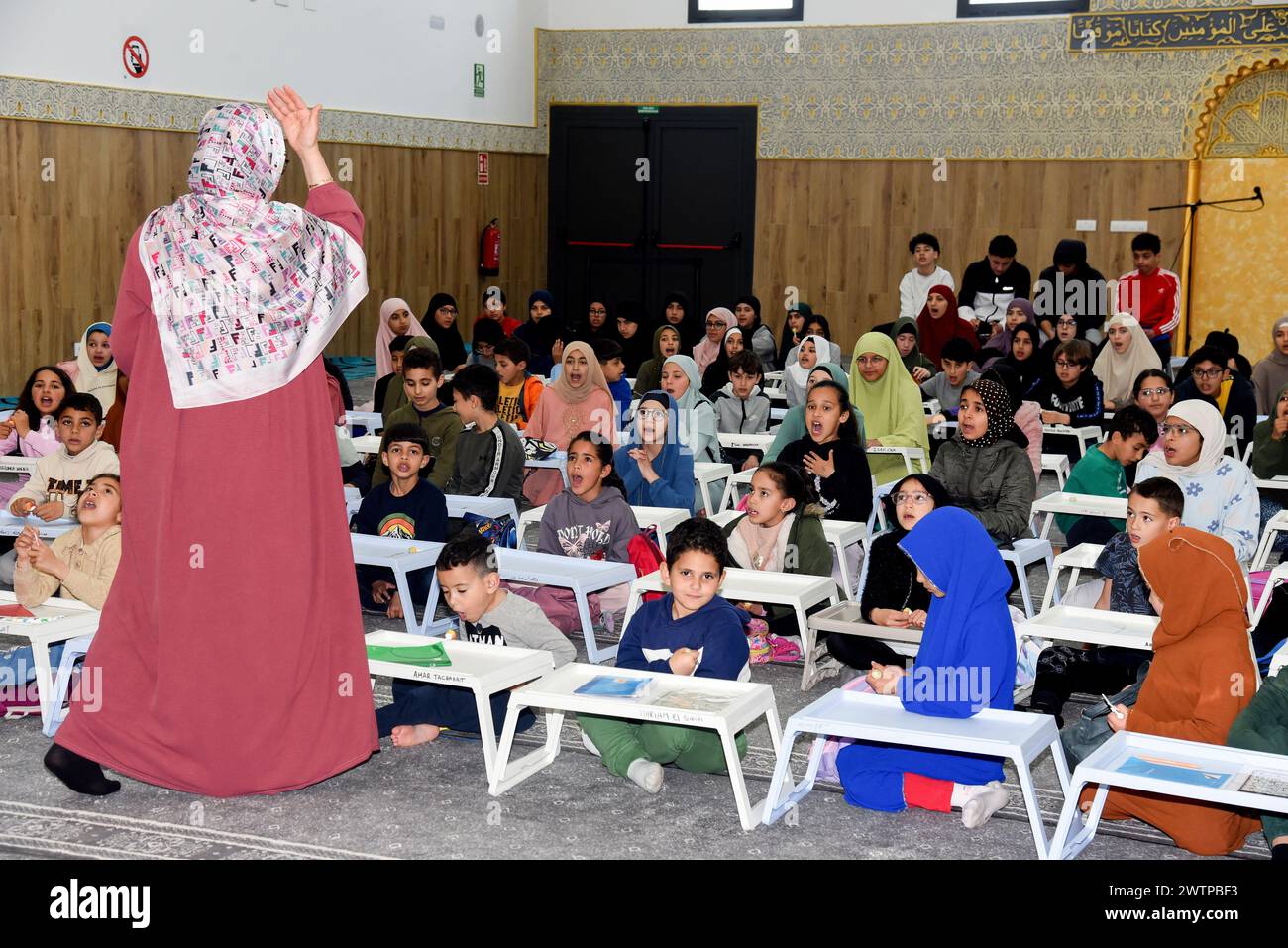 An Arabic teacher wearing a veil teaches her students to pray in a ...