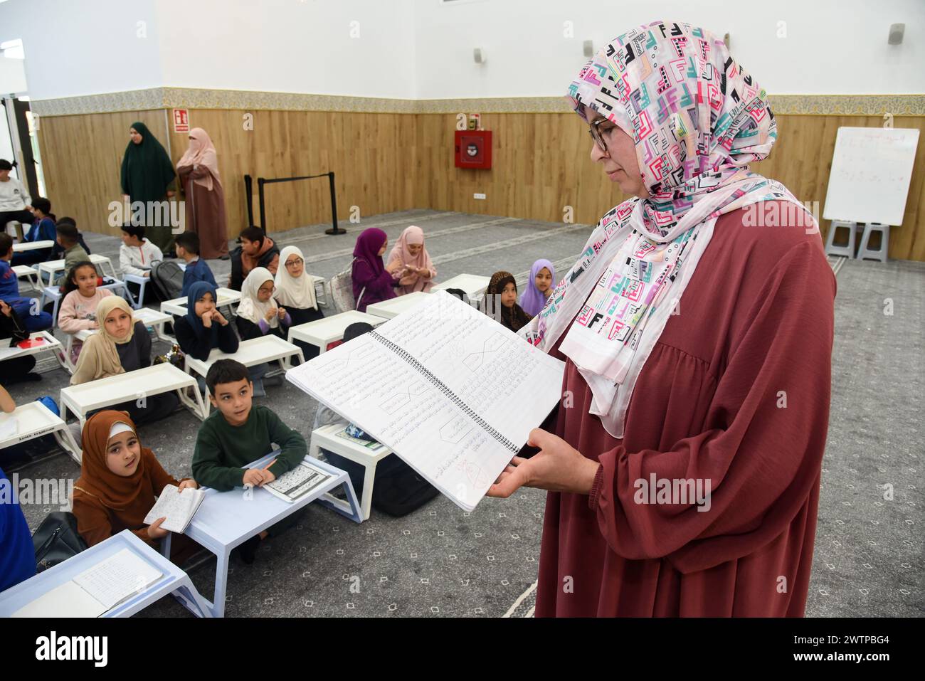 An Arabic teacher wearing an Islamic veil corrects a text in Arabic ...