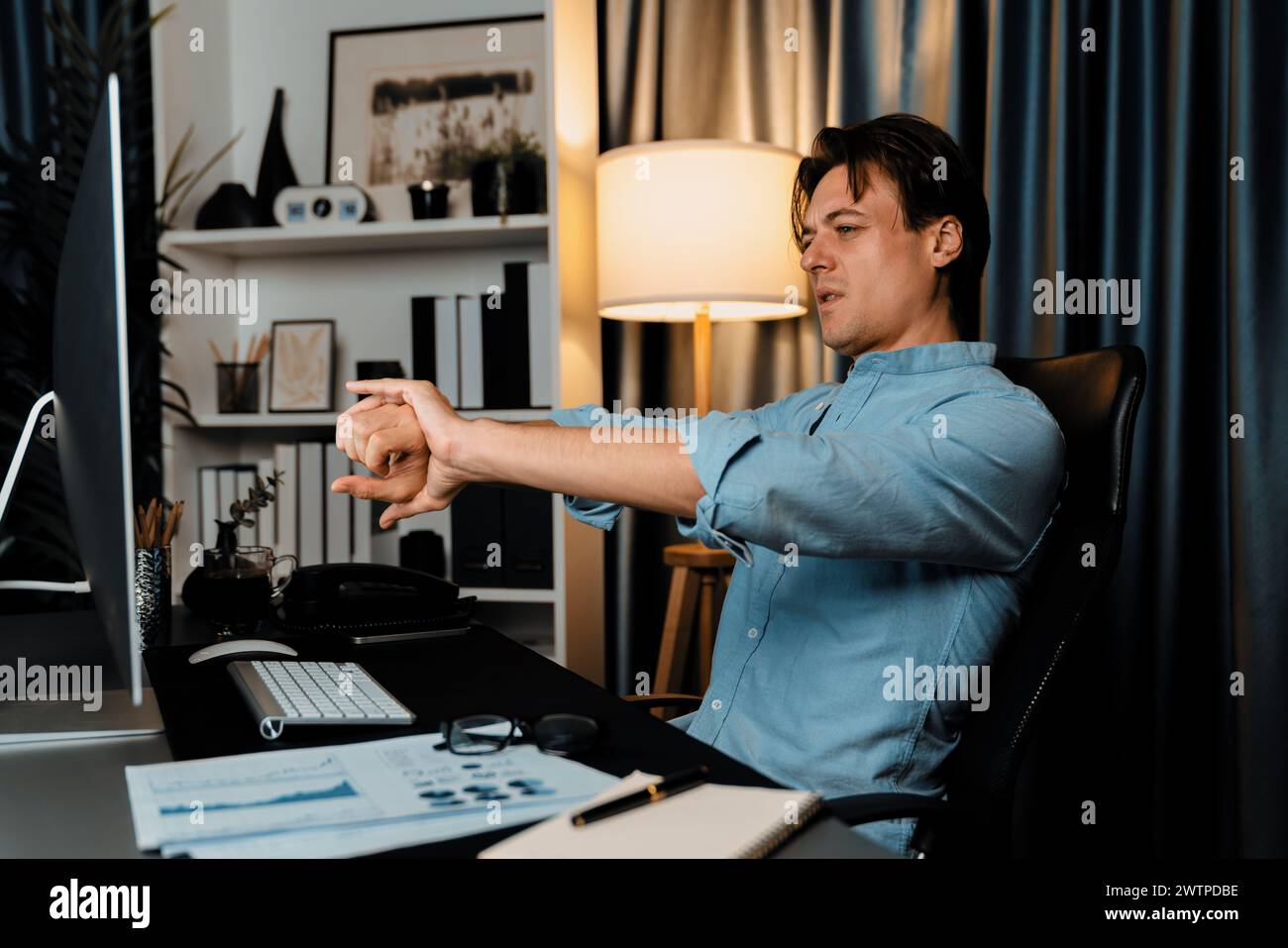 Sales manager working on desk with stretching arm up and down manner at ...