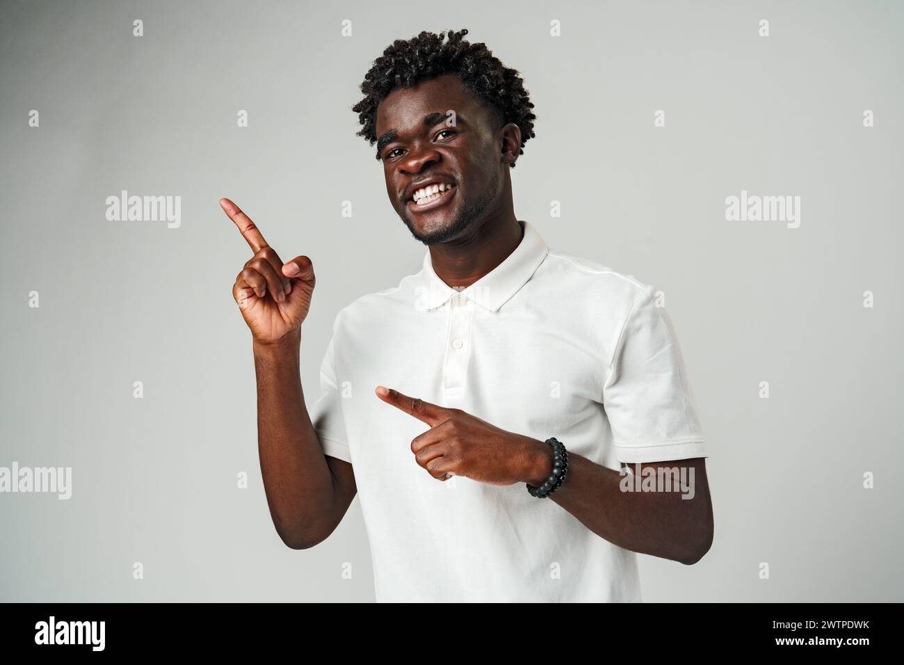 Young African Man Pointing at Something Against Gray Background Stock ...