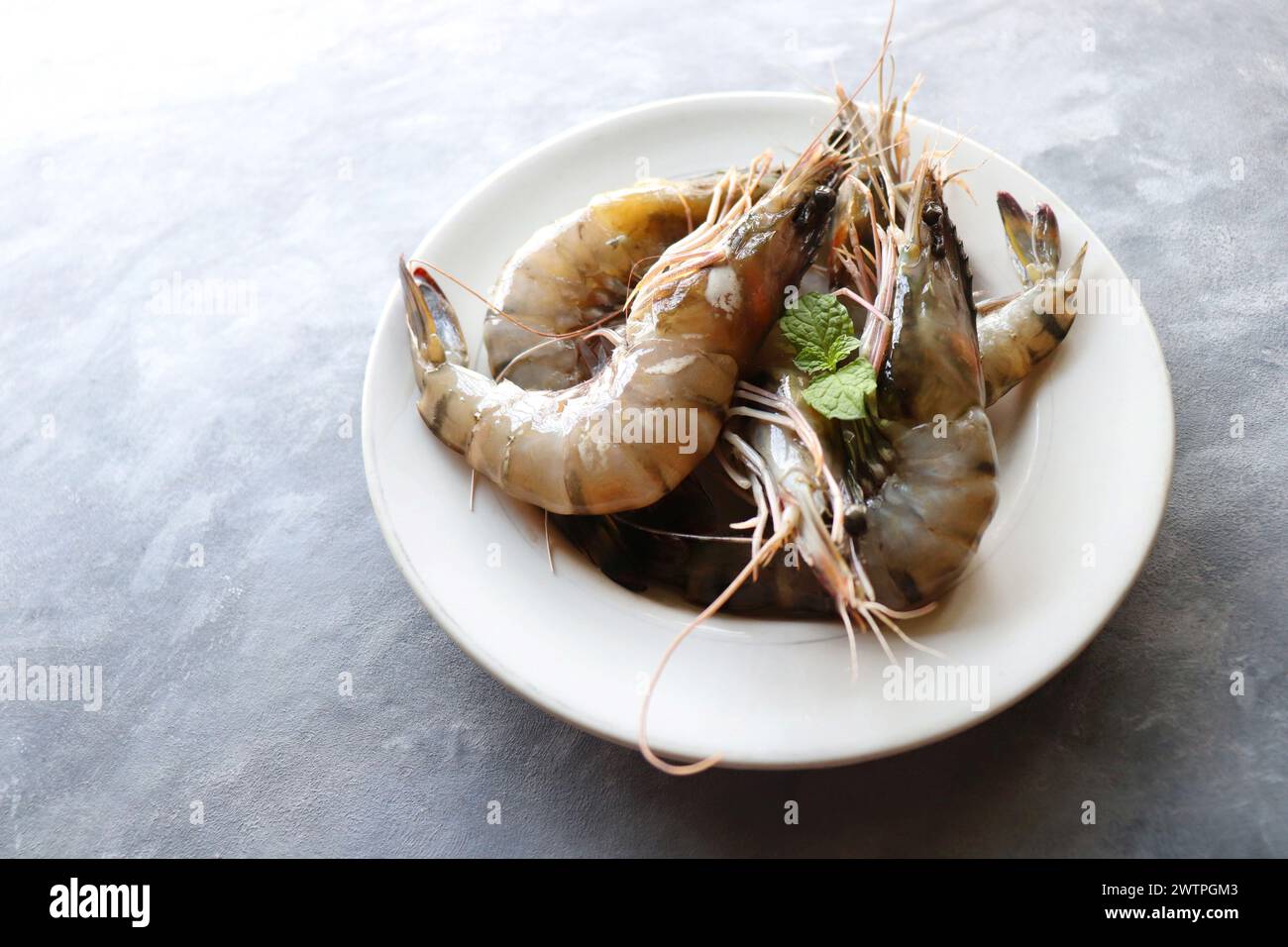 Fresh shrimp or black tiger prawns. Uncooked on a white ceramic plate ...