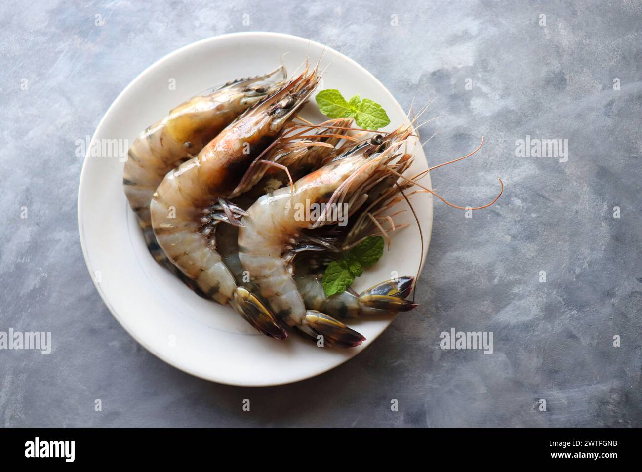 Fresh shrimp or black tiger prawns. Uncooked on a white ceramic plate ...