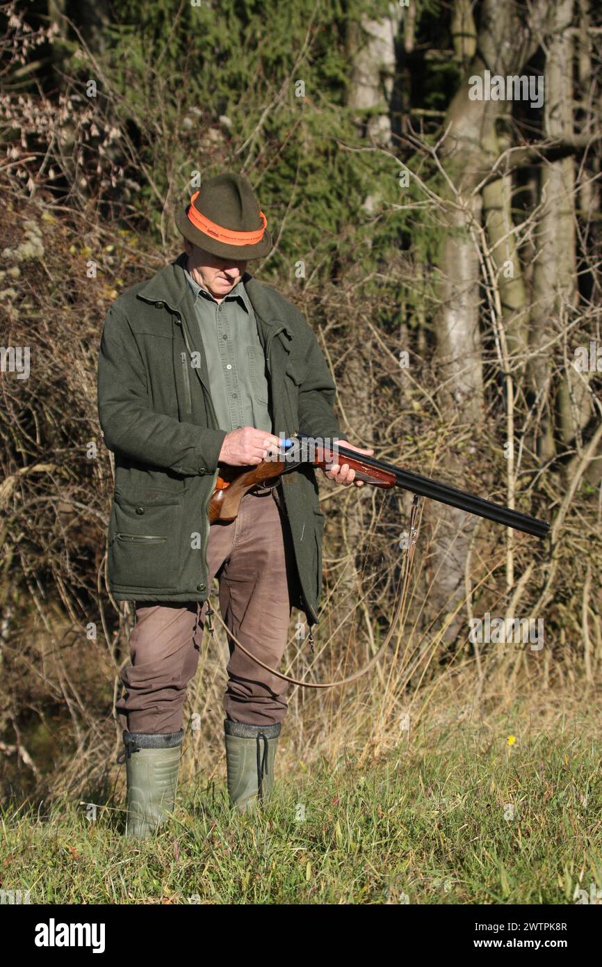 Hunter puts a shotgun shell into his rifle during a hunt for brown hare ...