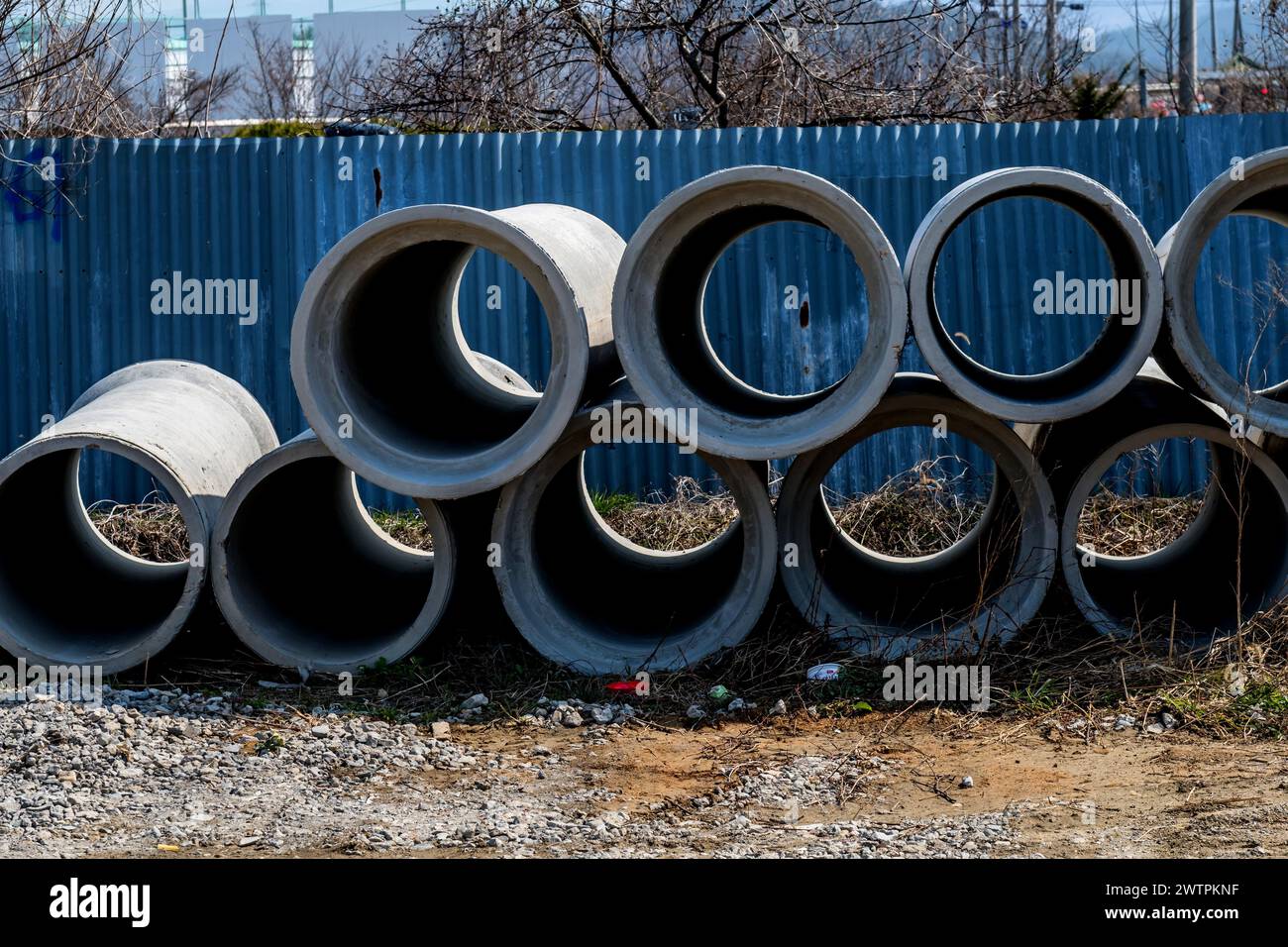 Round concrete culverts stacked in front of fence in countryside in ...