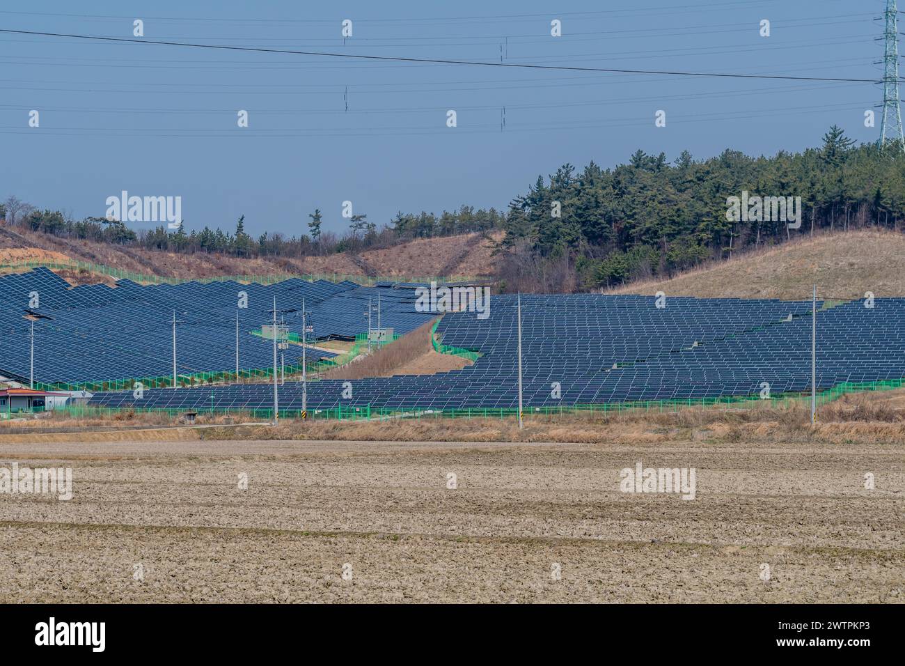 Solar panel array on hillside beside rural field under blue sky in ...